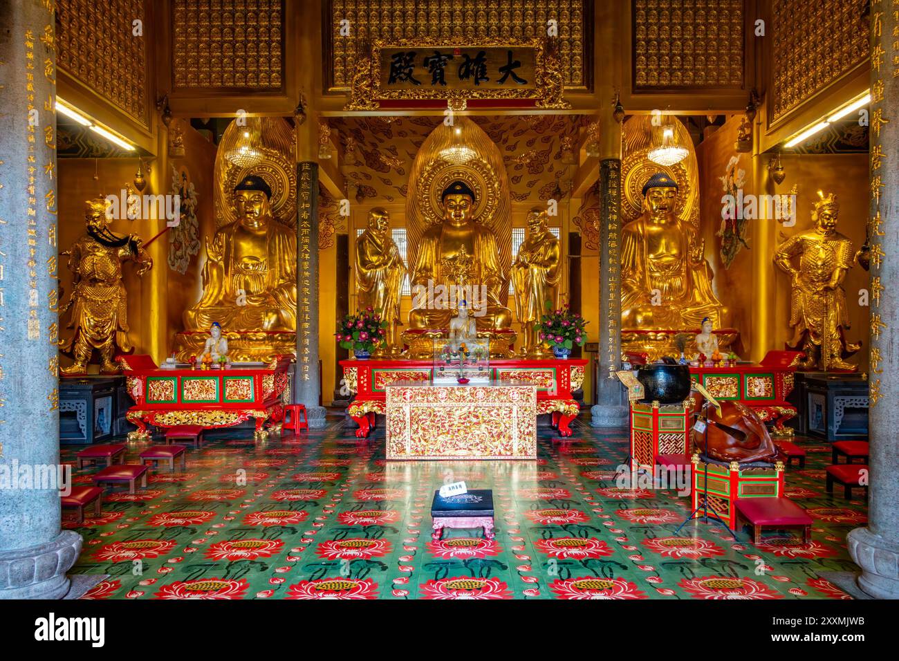 Three golden statues of Buddha sit behind an alter in a shrine at Tek ...