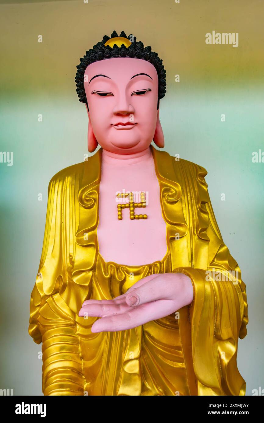 A Budhist idol, decadent in gold attire with a swastika on the chest at ...