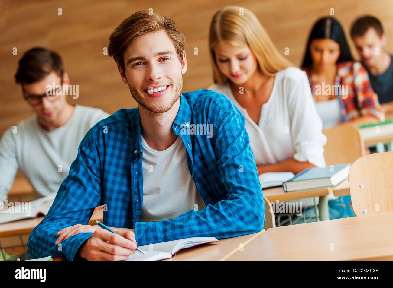 Showing a dedication to education. Handsome young man writing in note ...