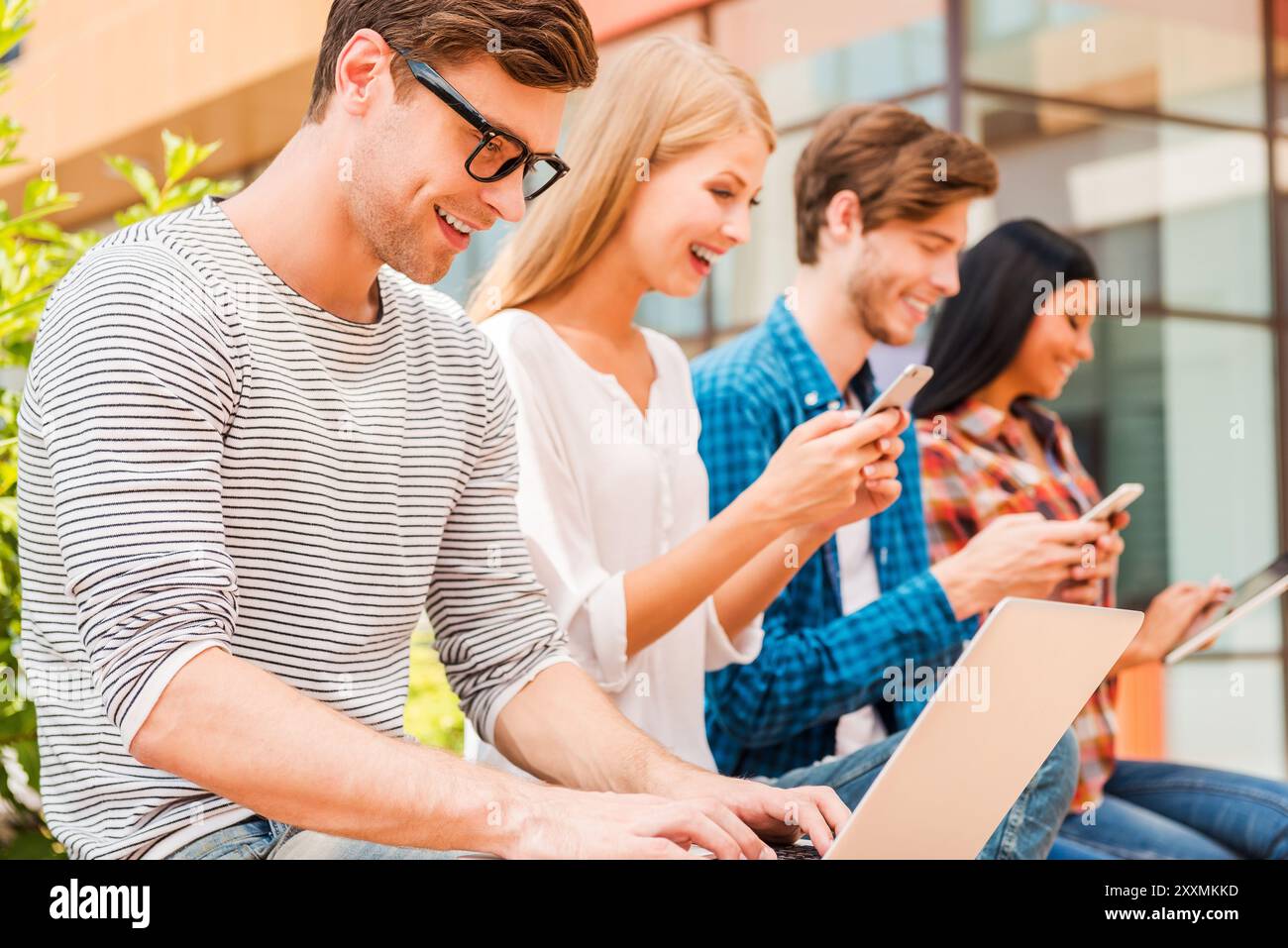 Living in digital age. Group of young people holding different digital ...
