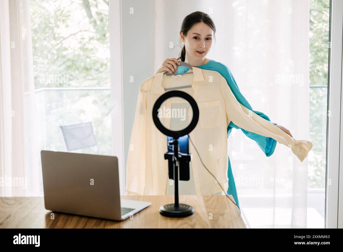 Fashion influencer showcasing yellow blouse with ring light and laptop ...