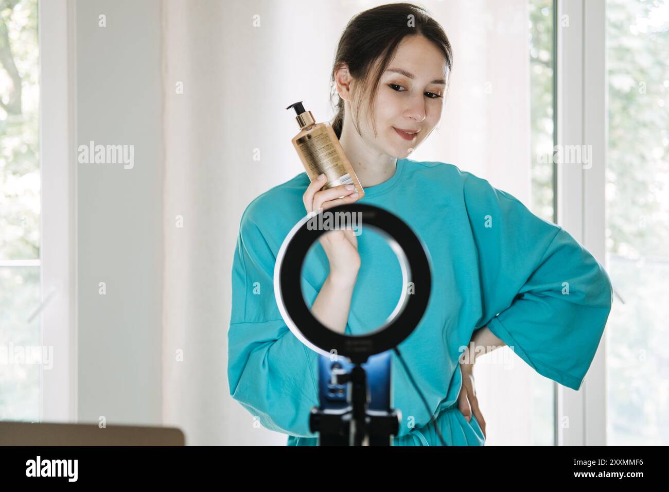 Beauty influencer demonstrating skincare product with ring light setup ...
