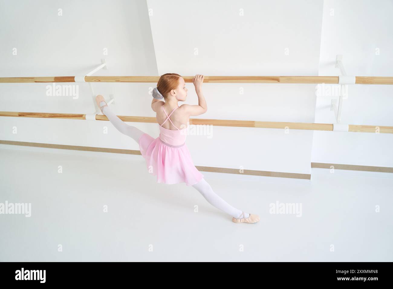 Young ballet girl at studio lesson. Training performance. Stretching ...