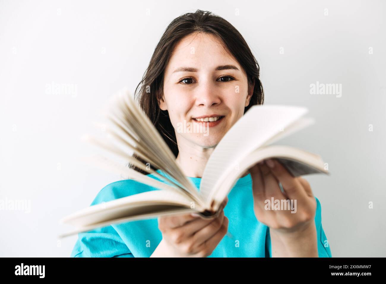 Woman smiling while holding an open book, symbolizing education ...