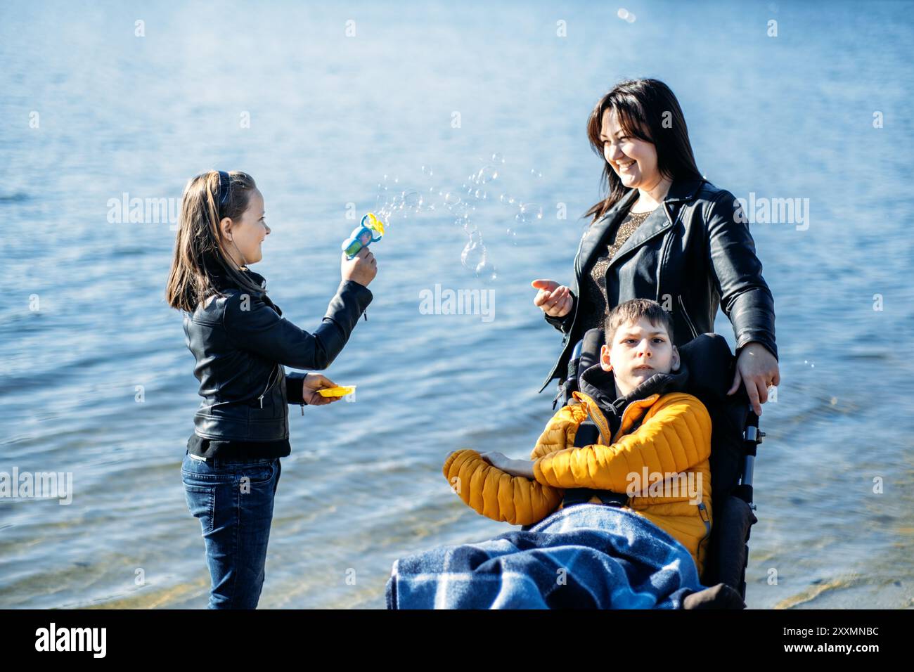 Mother and children enjoying outdoor time by the lake, inclusive family ...
