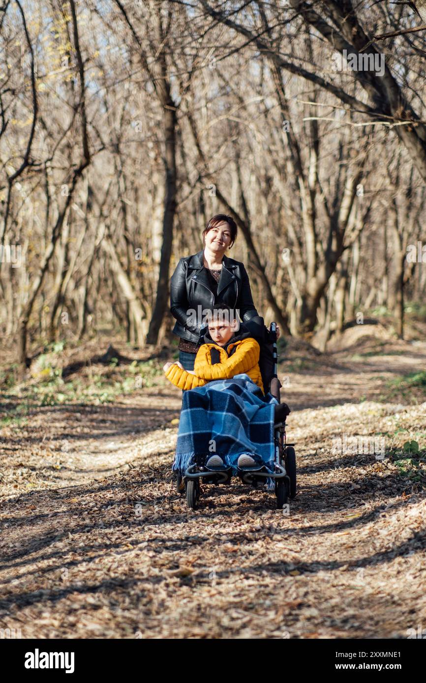 Mother and child with special needs enjoying nature walk in forest ...