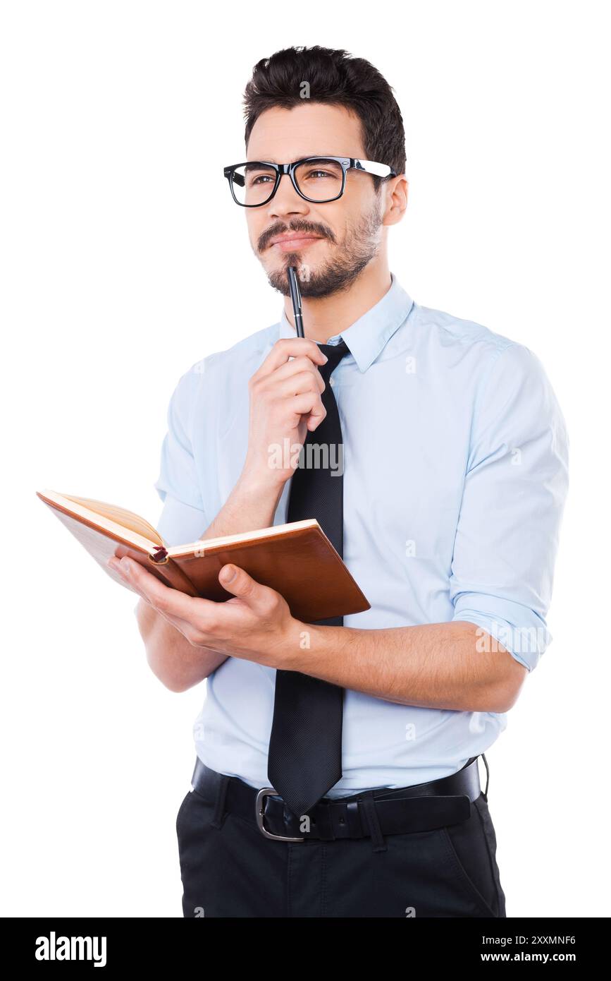 Just inspired. Thoughtful young man in shirt and tie making notes in ...