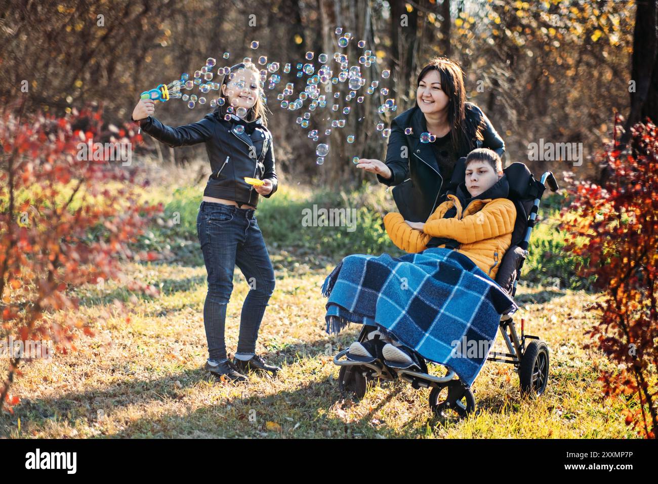 Mother and sibling spending quality time with child in wheelchair ...