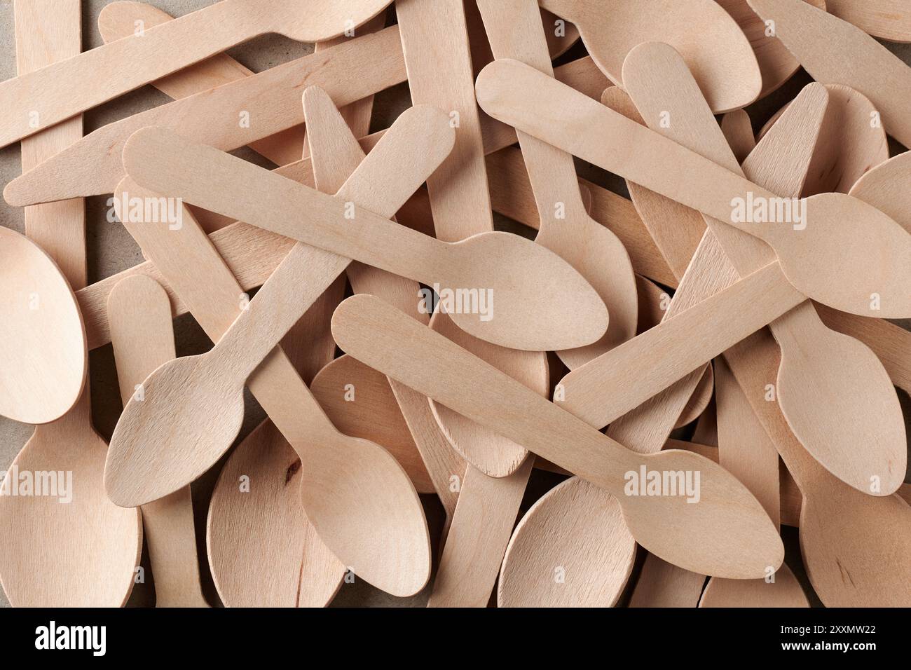 pile of disposable wooden spoons in full frame background, eco-friendly ...