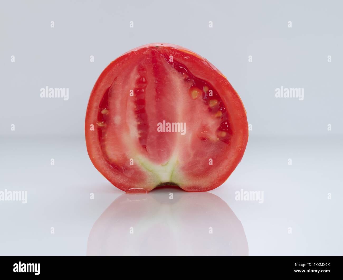 A juicy tomato sliced in half standing on a white background Stock ...