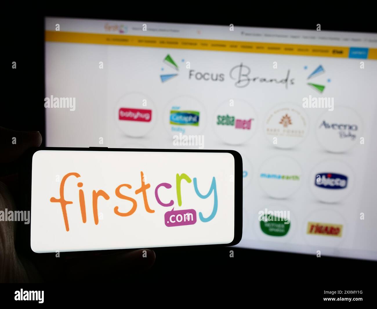 Person holding mobile phone with logo of Indian kid products e-commerce ...