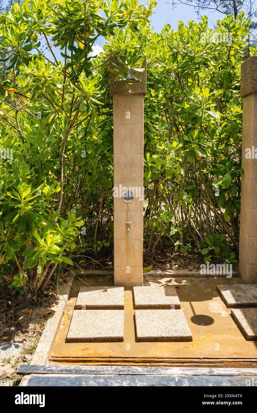Outdoor shower facility with stone tiles and lush greenery Stock Photo ...