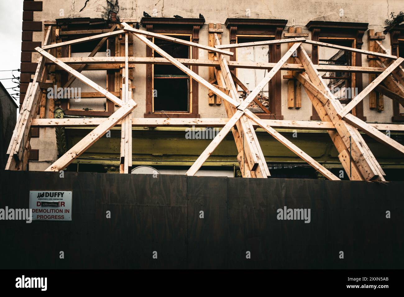 Workers are busy reinforcing a dilapidated structure with wooden beams ...