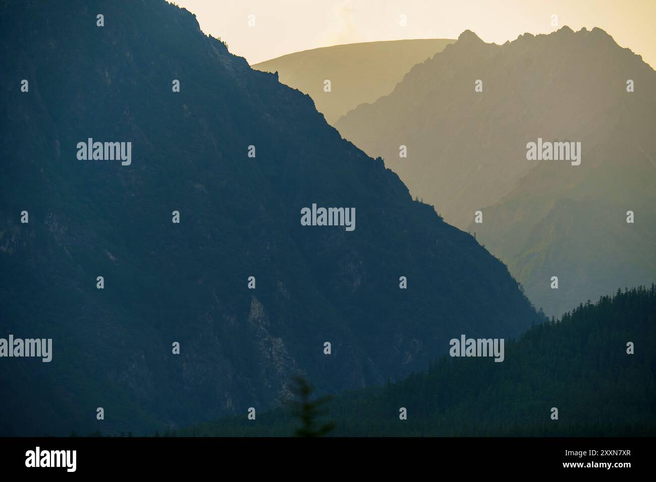 Mountain peaks in silhouette, layered in shadows as dusk falls ...