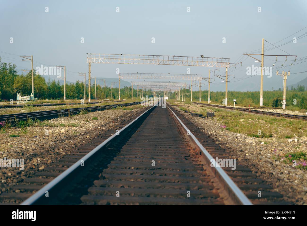 A straight railway track extends into the horizon, flanked by power ...
