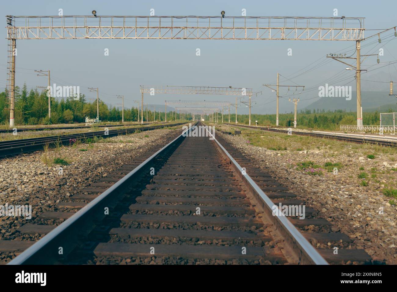A straight railway track extends into the horizon, flanked by power ...
