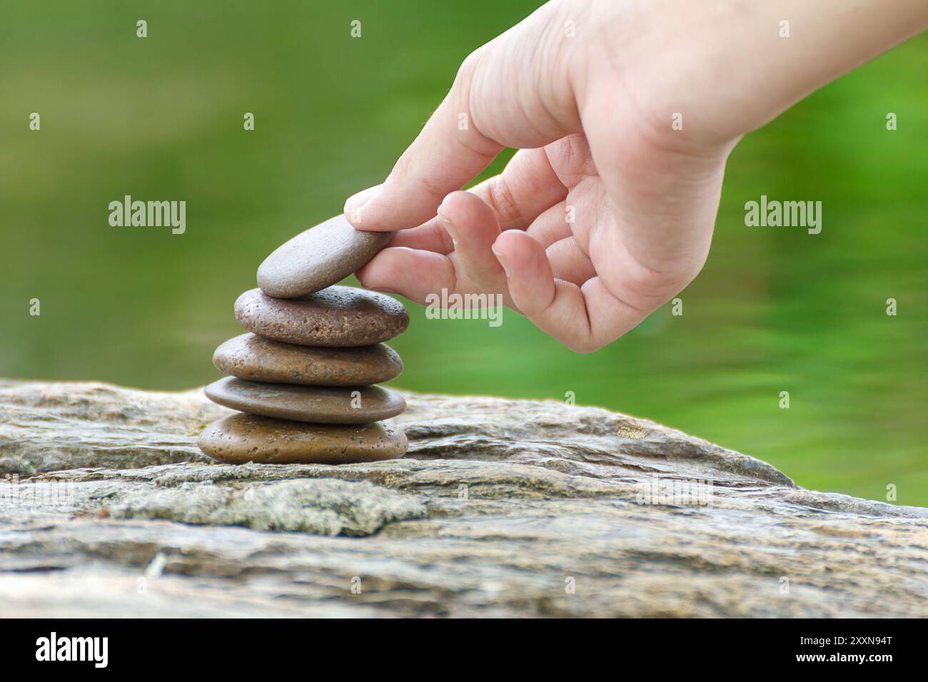 Zen concept, Hand put stone building a pile of zen stones Stock Photo - Alamy