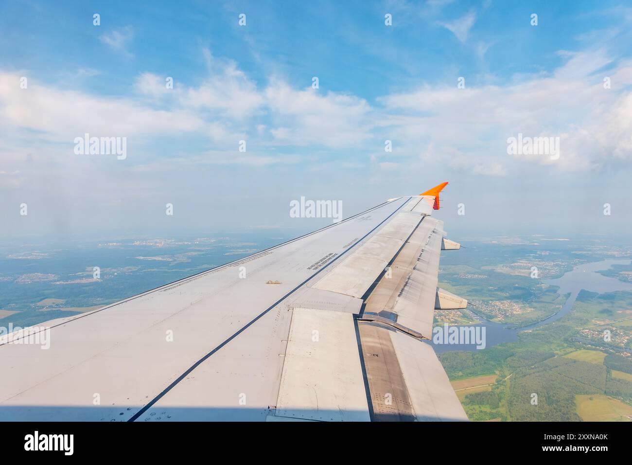 View of airplane wing, blue skies and green land during landing ...