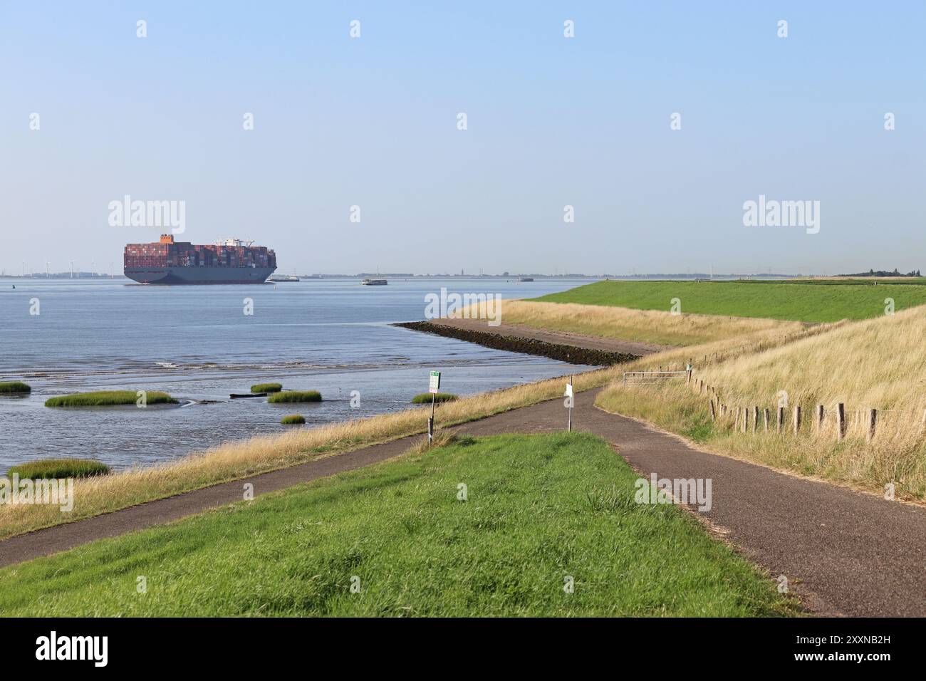a beautiful coast landscape in zeeland of a big ship underway to the ...