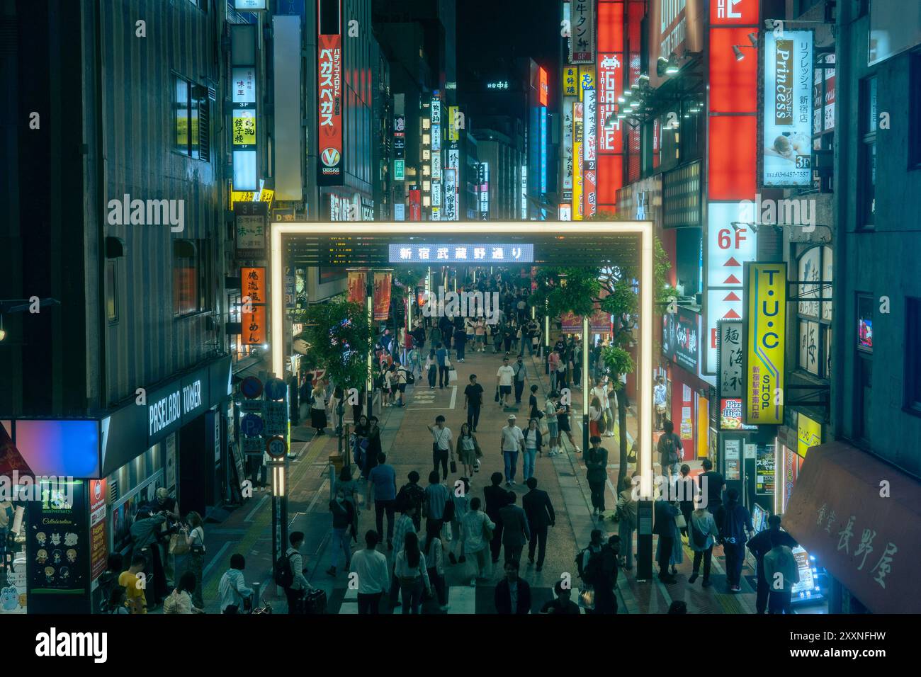 Crowds walking beneath neon signs and a glowing entrance arch in a ...