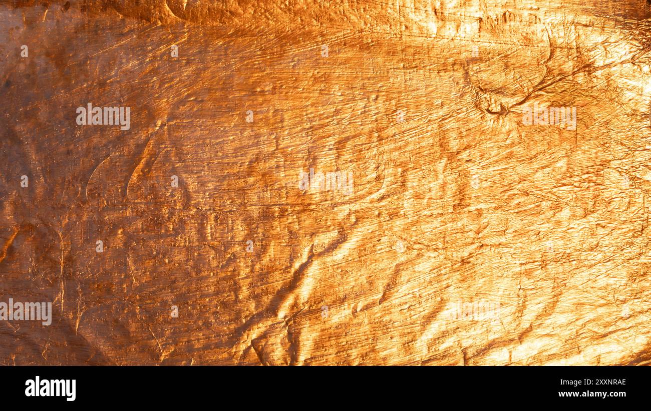 Crumpled shiny metallic texture in golden color forming an abstract ...