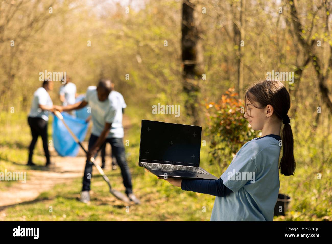 Small girl using isolated display on laptop during litter cleanup ...