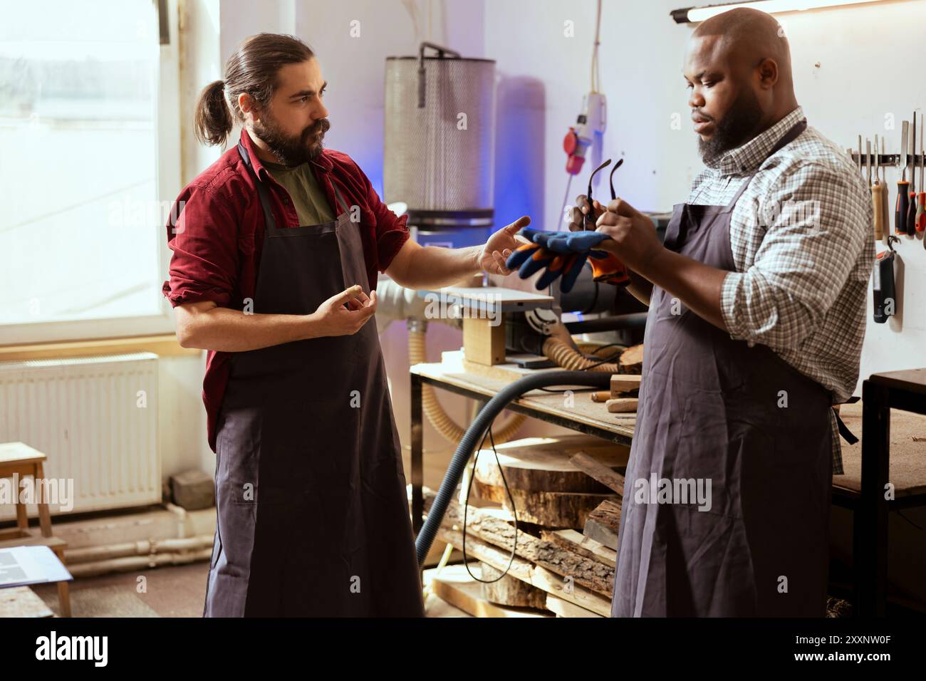 Apprentice preparing to start production in furniture assembly shop, receiving safety gear from ...