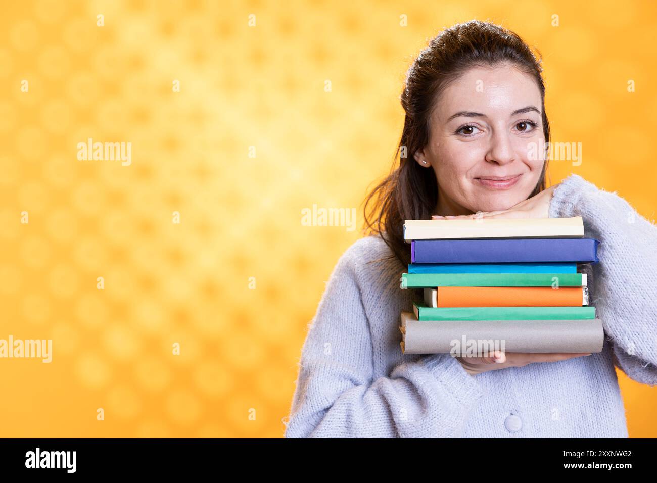 Portrait of happy woman holding pile of books, portraying reading ...