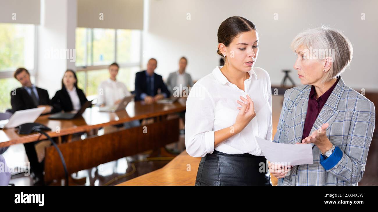 Strict director checking documents from a female manager in meeting ...