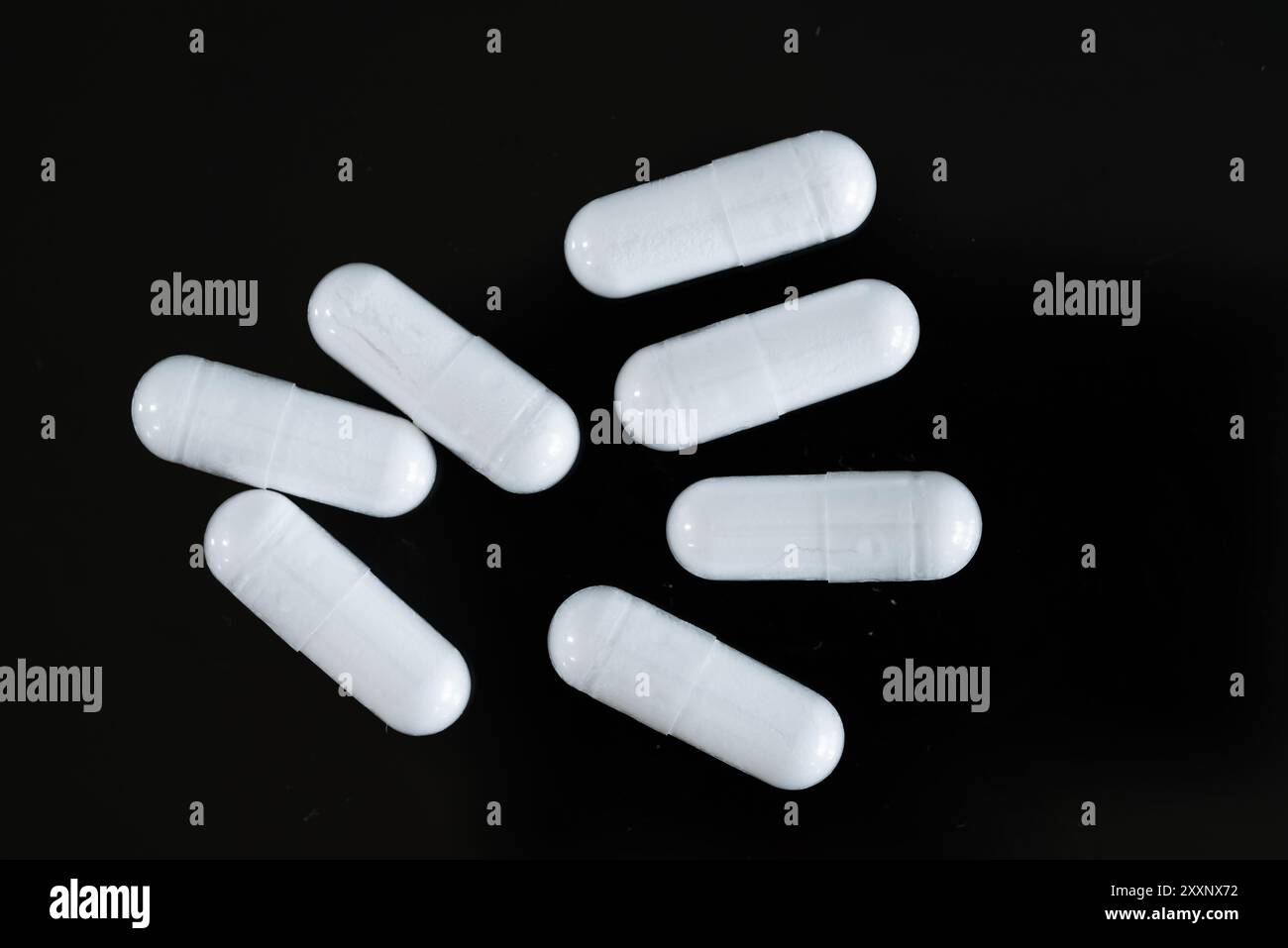 white vitamins supplement capsules over a black background Stock Photo ...