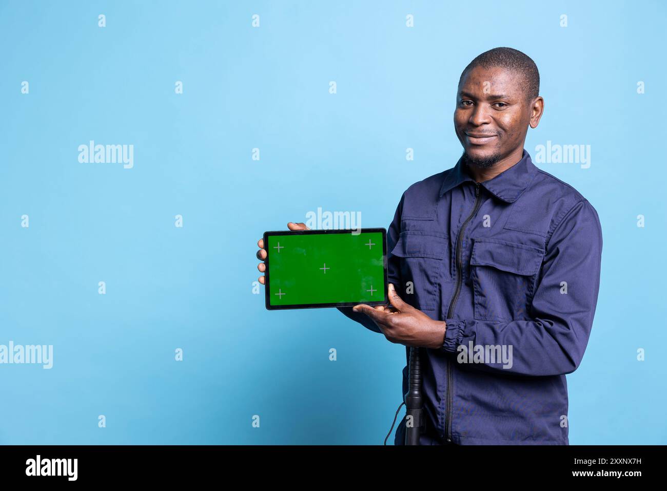 Confident happy bodyguard showing a greenscreen on his tablet, posing ...