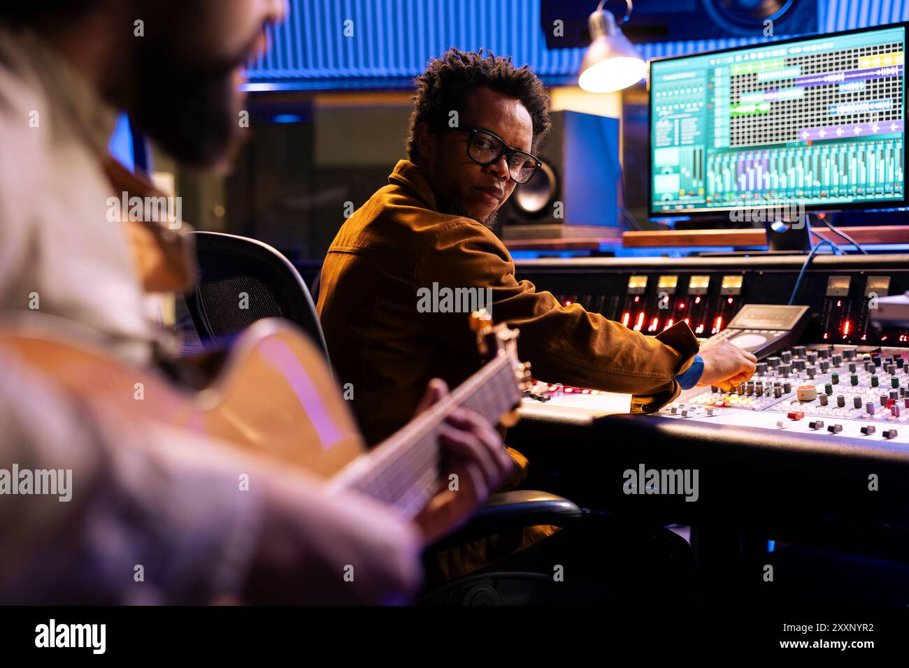 Musician composing a new record with his guitar and mixing console in ...