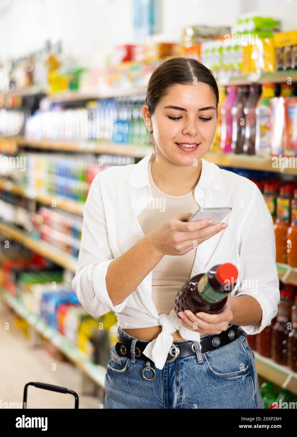 Girl scanning barcode on juice bottle with phone in supermarket Stock Photo - Alamy