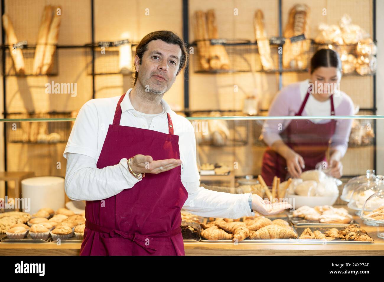 Baker wearing apron while working behind counter in small bakery Stock ...