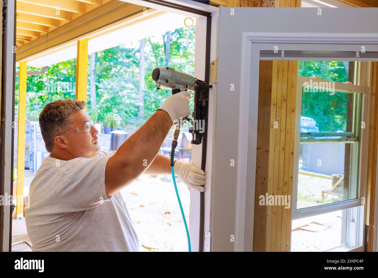 Use of pneumatic nail gun is demonstrated by carpenter while installing ...