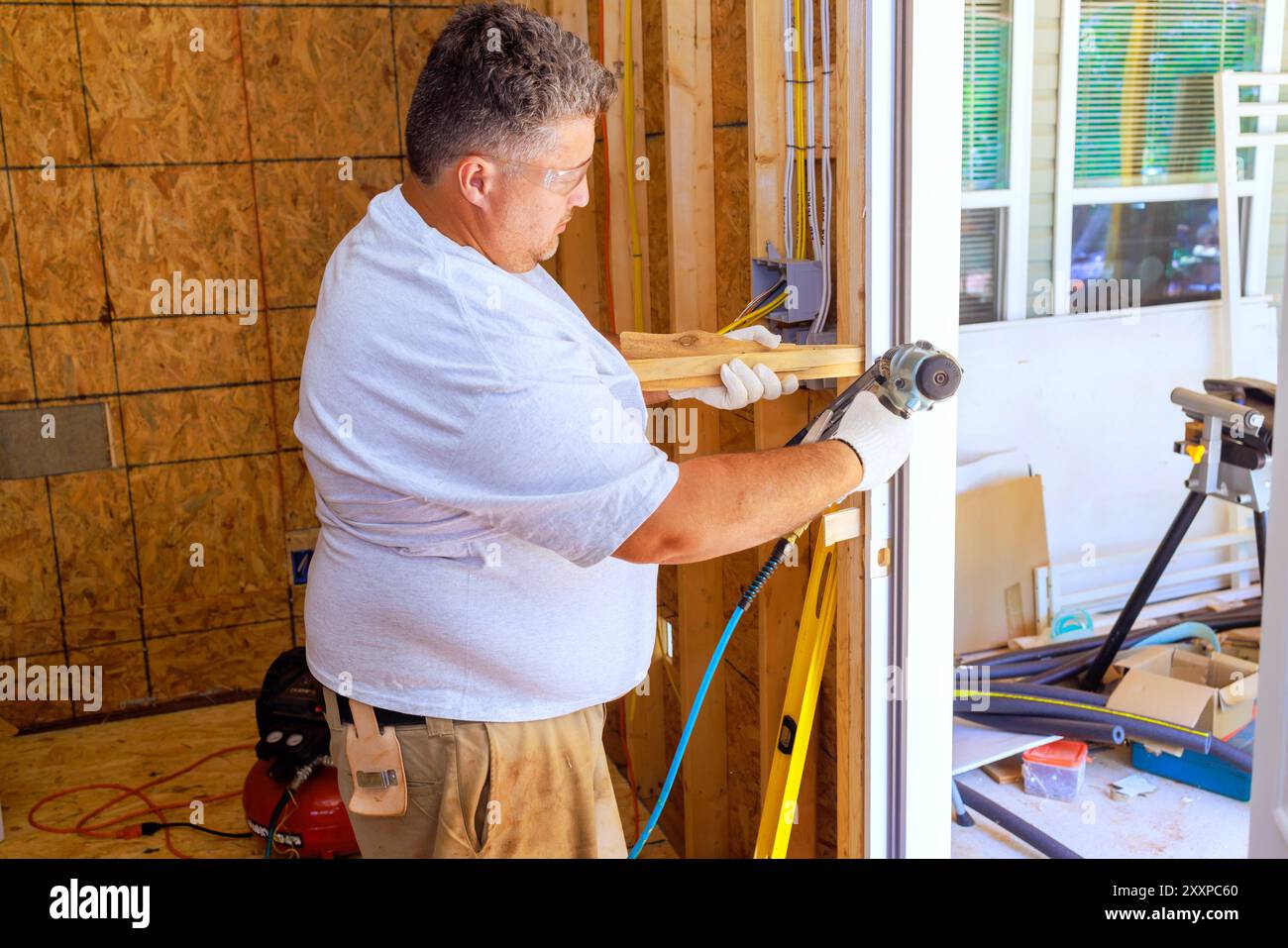 Installing new front door with pneumatic nail gun by carpenter Stock ...