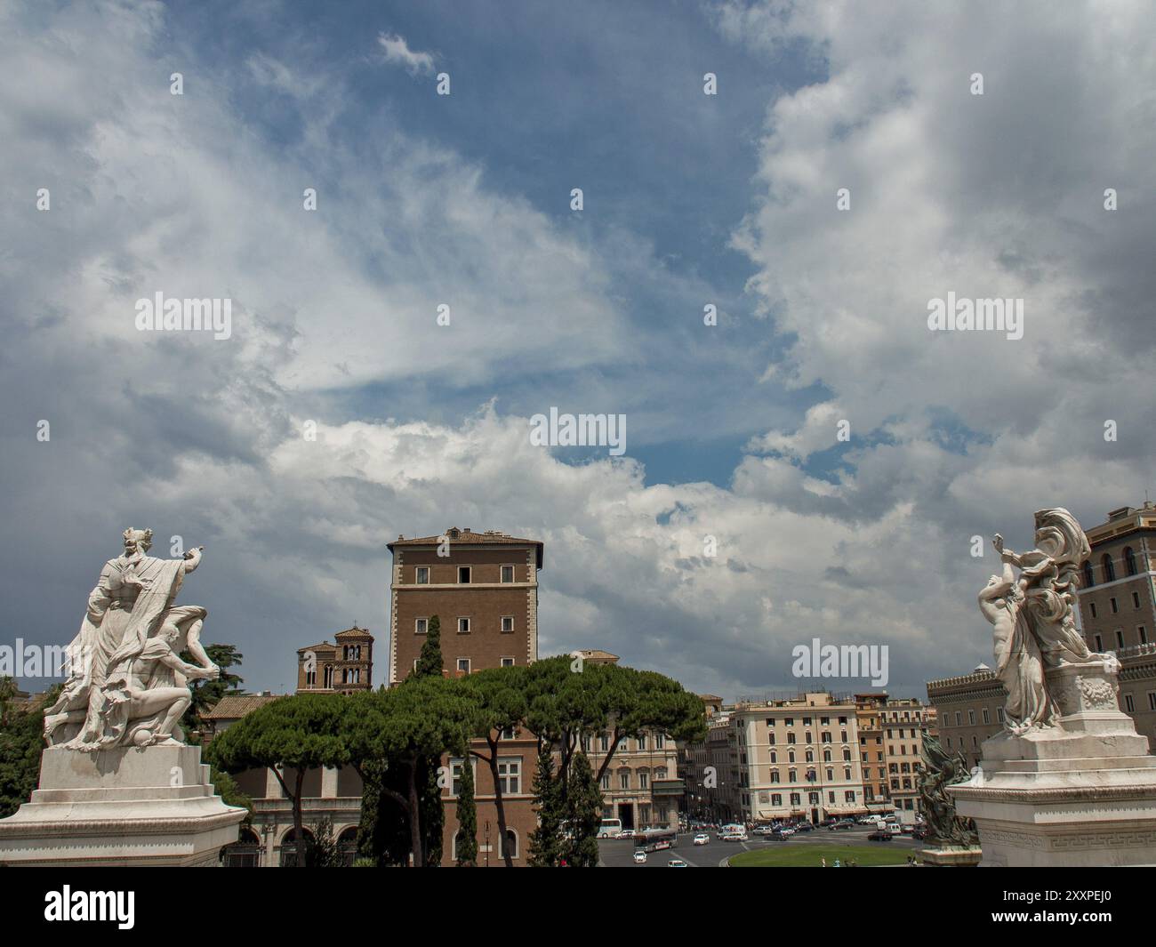 Ancient sculptures frame a view of trees and historic buildings under a ...