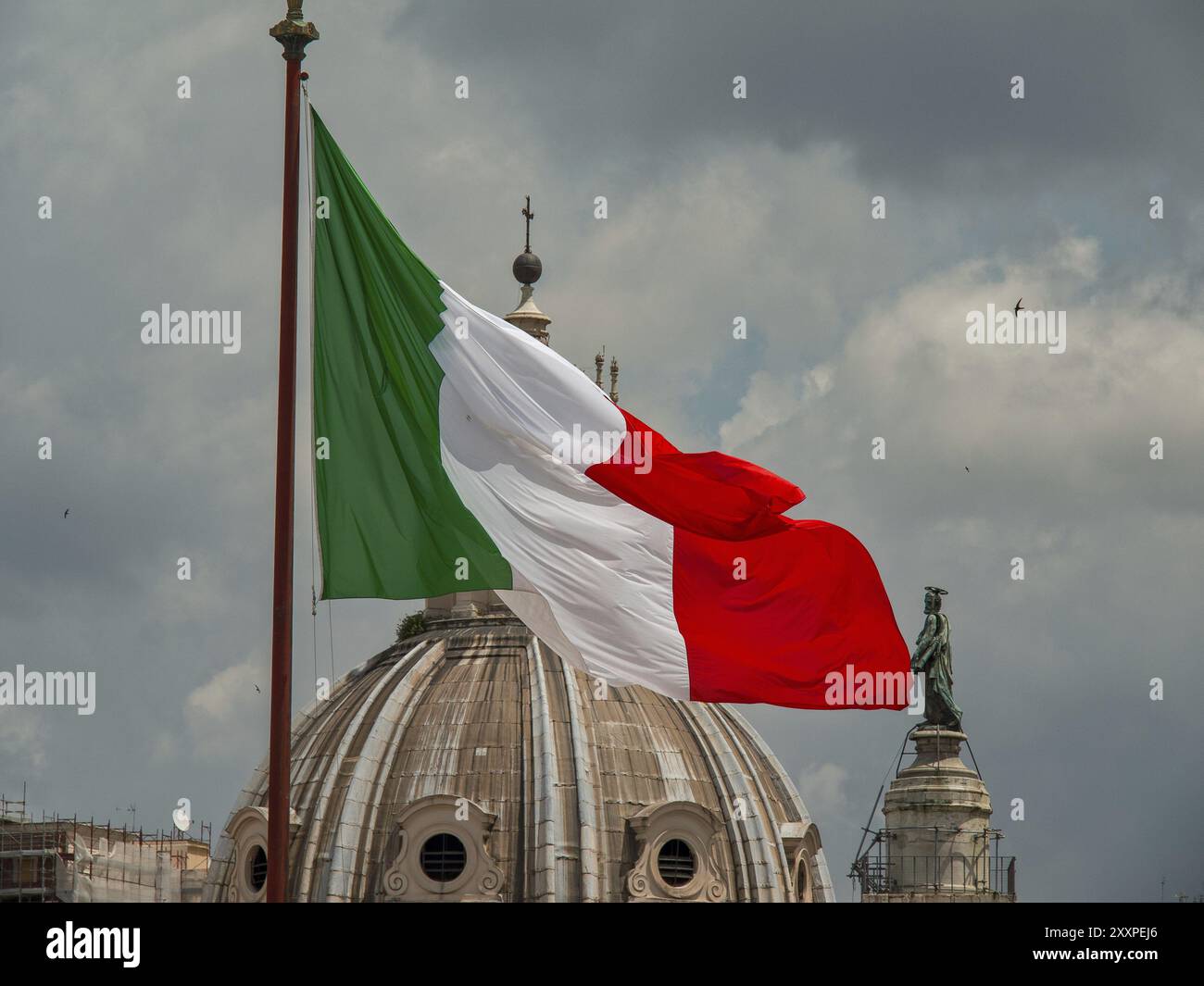 The Italian flag flies in front of a dome and a sculpture under a ...