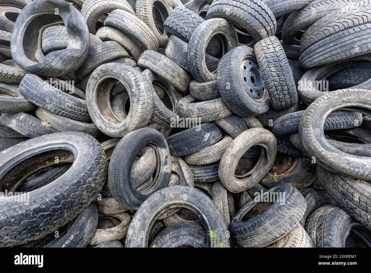 Old broken car tyres piled up up to form a mountain as a background ...