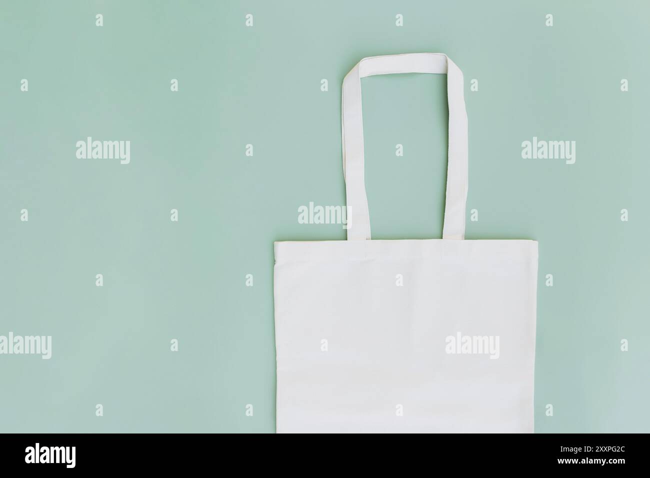 Eco white craft paper bag flat lay on green background with copy space ...