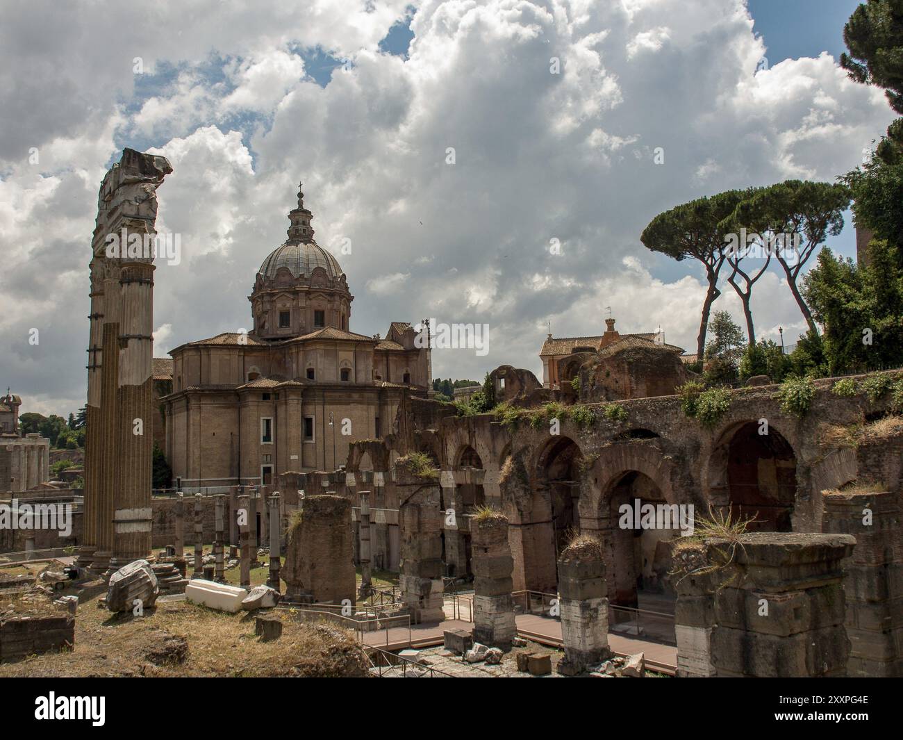 Ancient ruins next to a church with a dome under a wide sky with dense ...