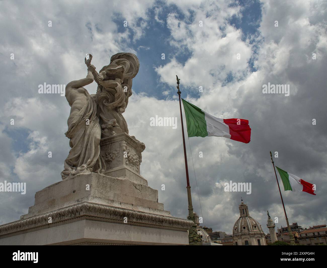Marble statue and two Italian flags waving under a cloudy sky, Rome ...