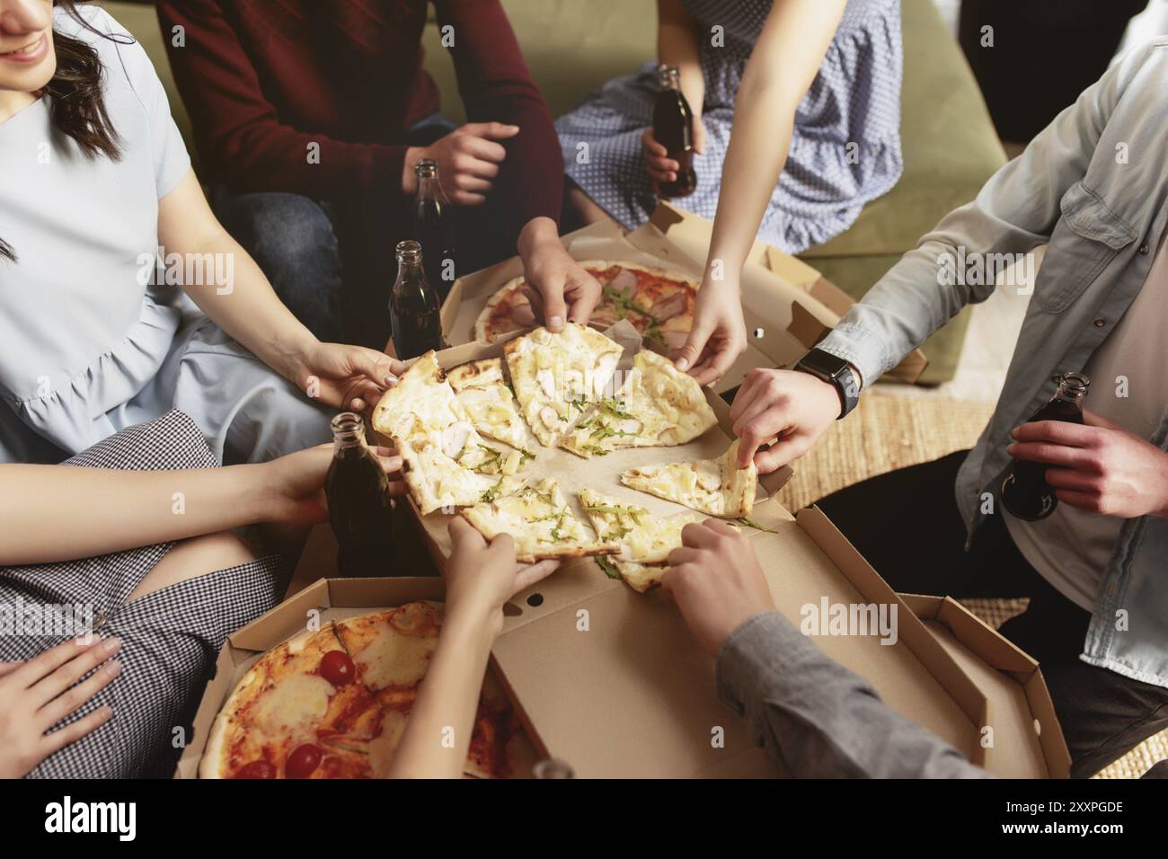 A pizza party, a group of friends chatting and happily eating pizza at ...