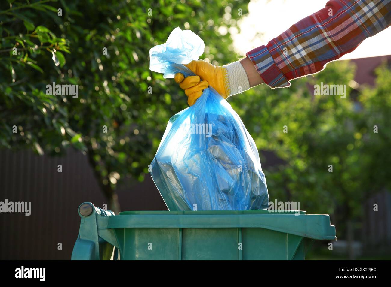 Man throwing trash bag into bin outdoors, closeup Stock Photo - Alamy