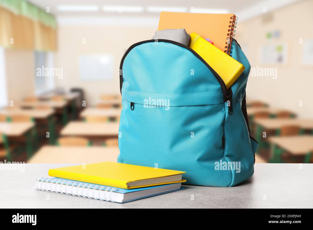 Light blue backpack with stationery on school desk in classroom Stock ...