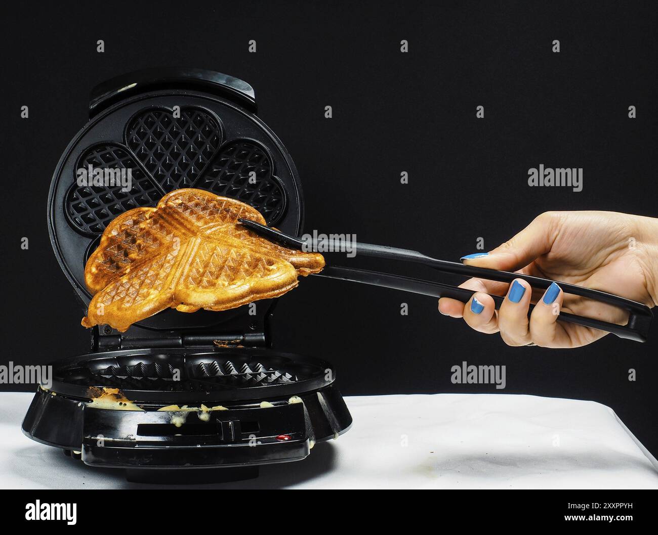 Female person making fresh waffles with a waffle maker towards black on ...