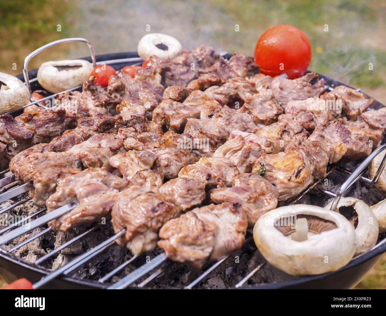 Shish kebab prepared over a black round shaped charcoal barbecue ...