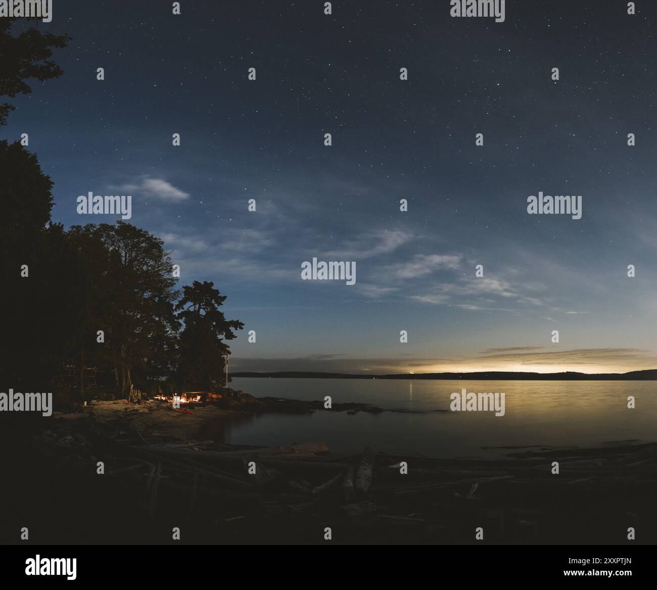 A serene lakeside scene with a starry night sky, trees, and a distant ...