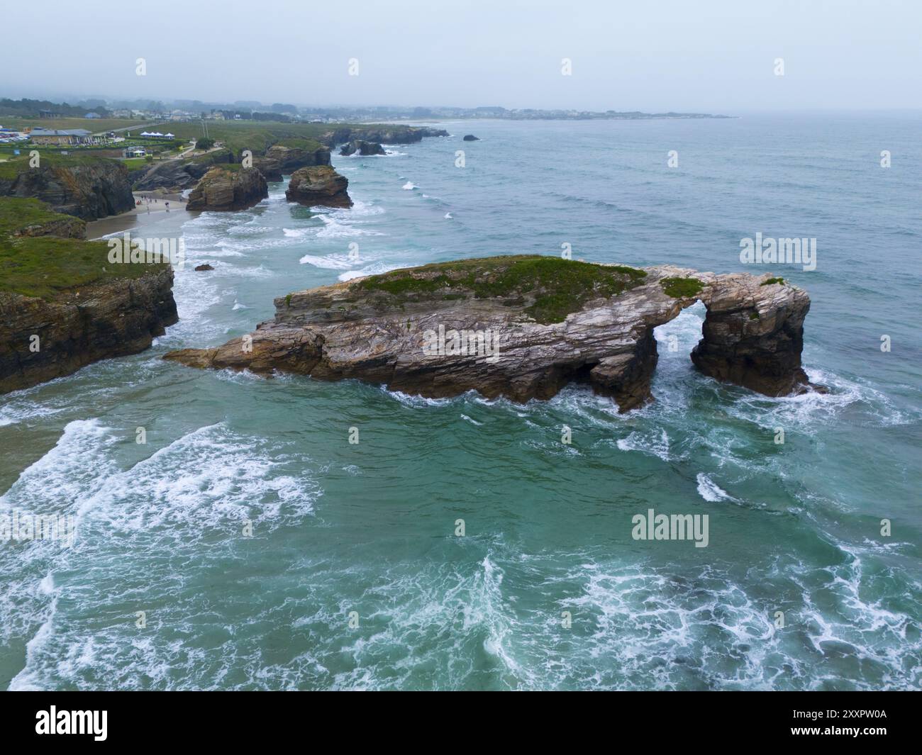 A striking rock in the shape of a natural bridge, surrounded by foaming ...