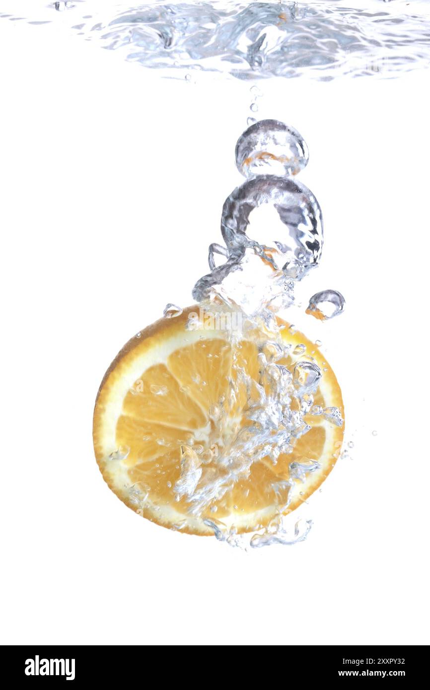 Orange falls into water on a white background Stock Photo - Alamy